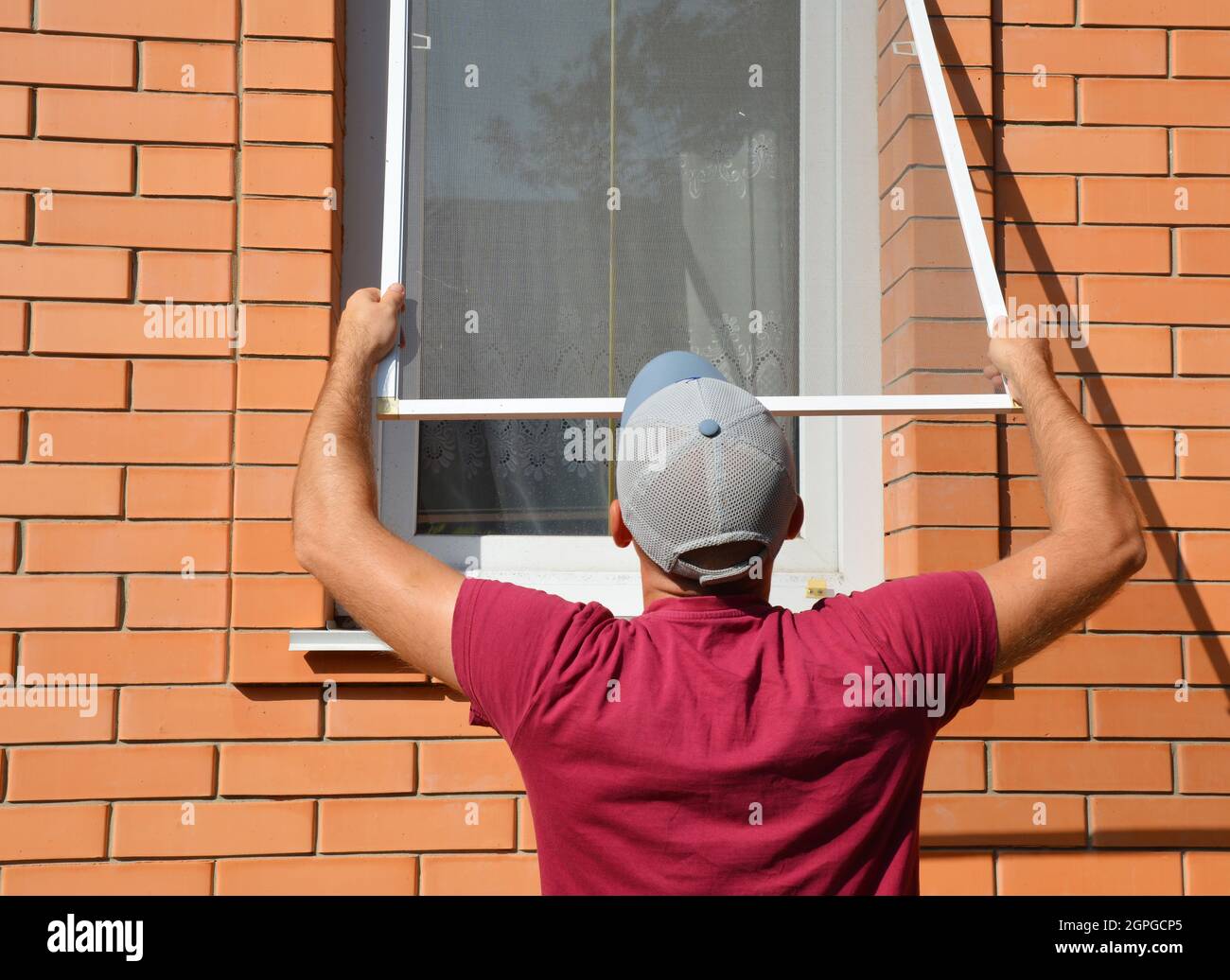 Contractor installing mosquito wire screen on house window to protect ...