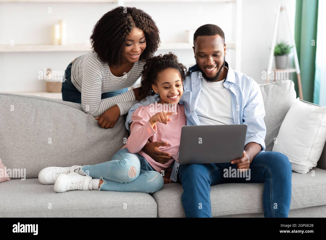 Happy black family of three using laptop in living room Stock Photo - Alamy