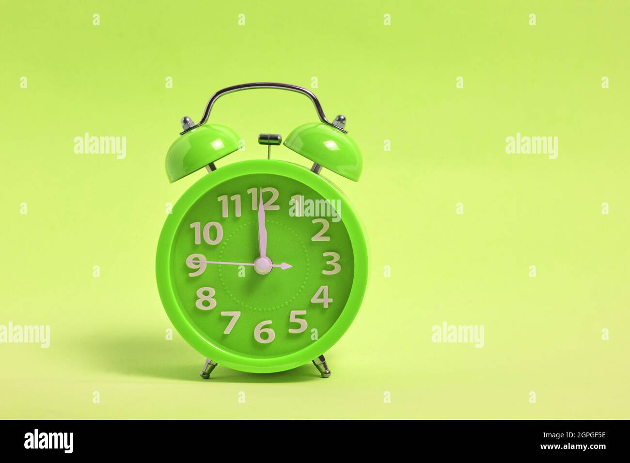 Alarm clock is green on a bright green background.Lunch time, twelve ...