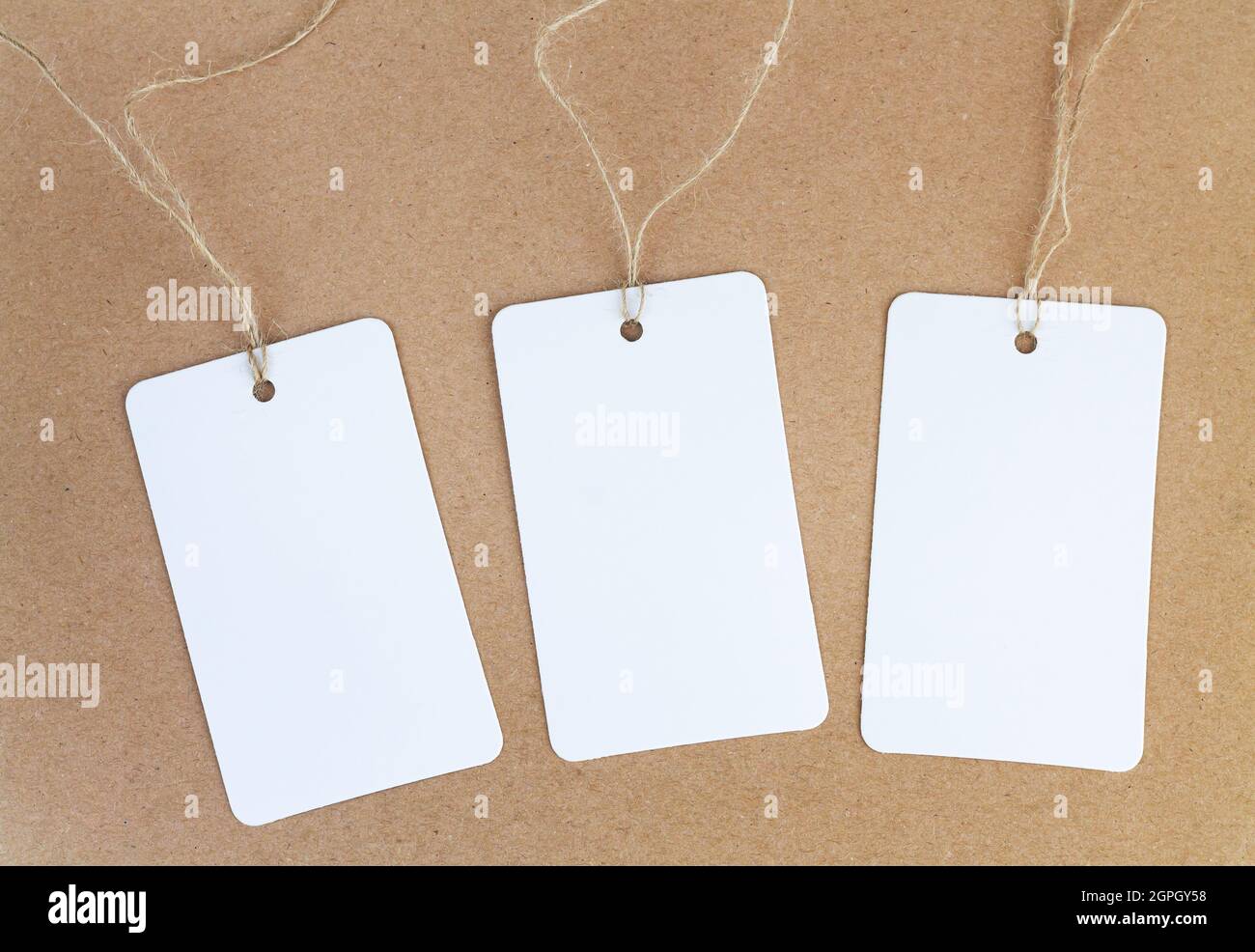 Set of three blank white paper cloth labels or price tags on brown ...