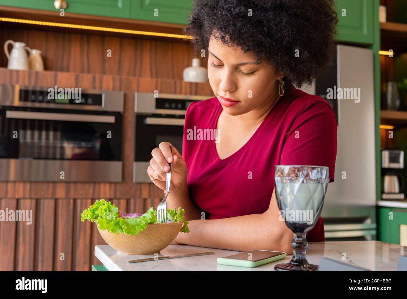 african american woman eating healthy meal with salad in kitchen ...