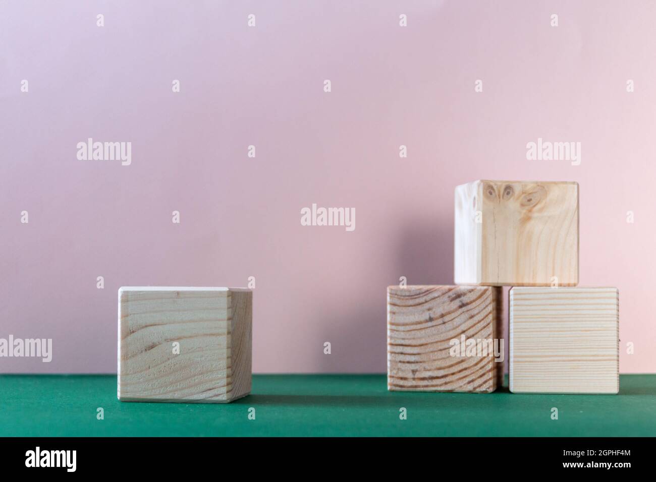 wooden cubes still life against pale pink and emerald green background ...
