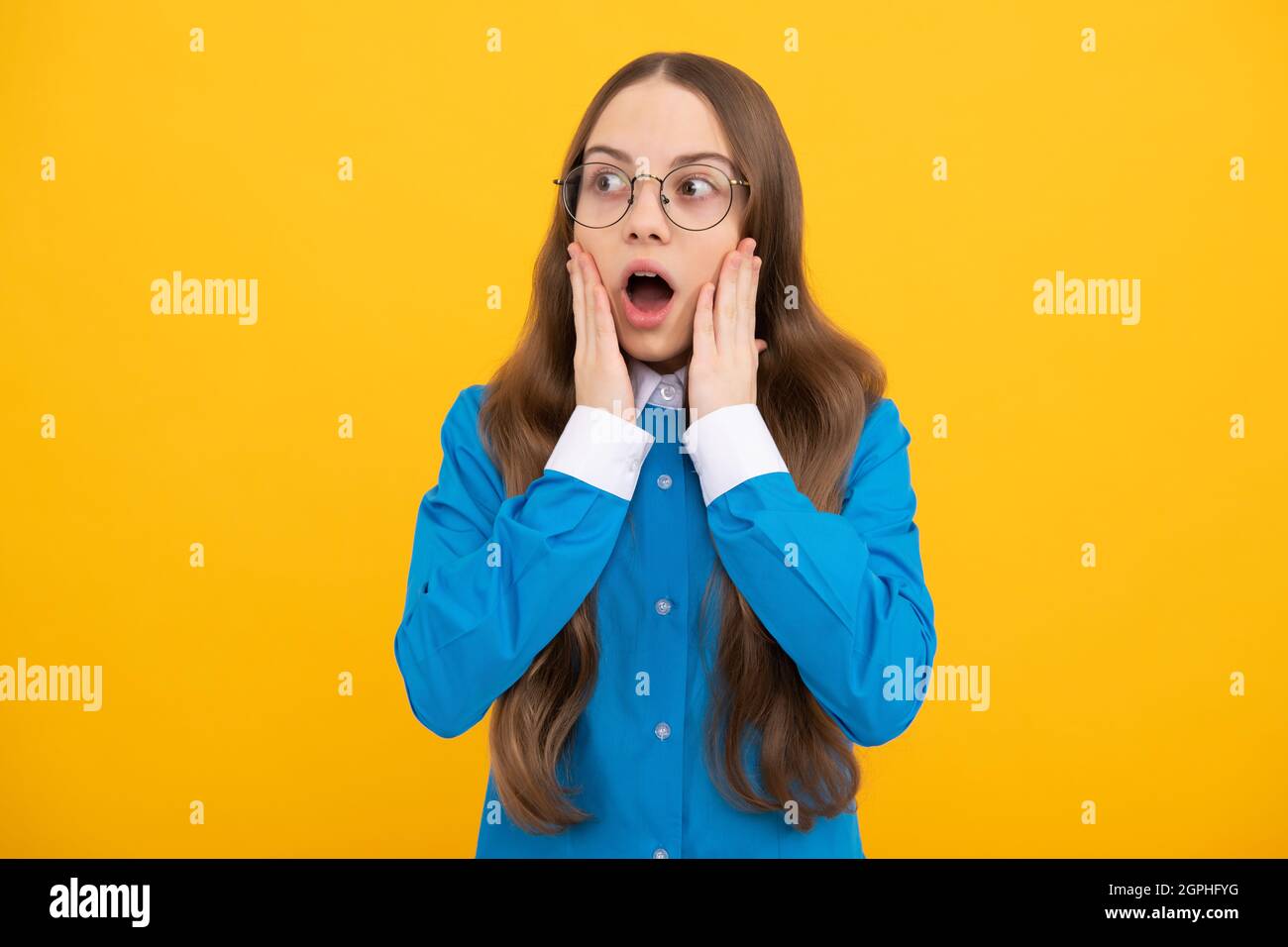 Shocked girl child in eyeglasses school education yellow background ...