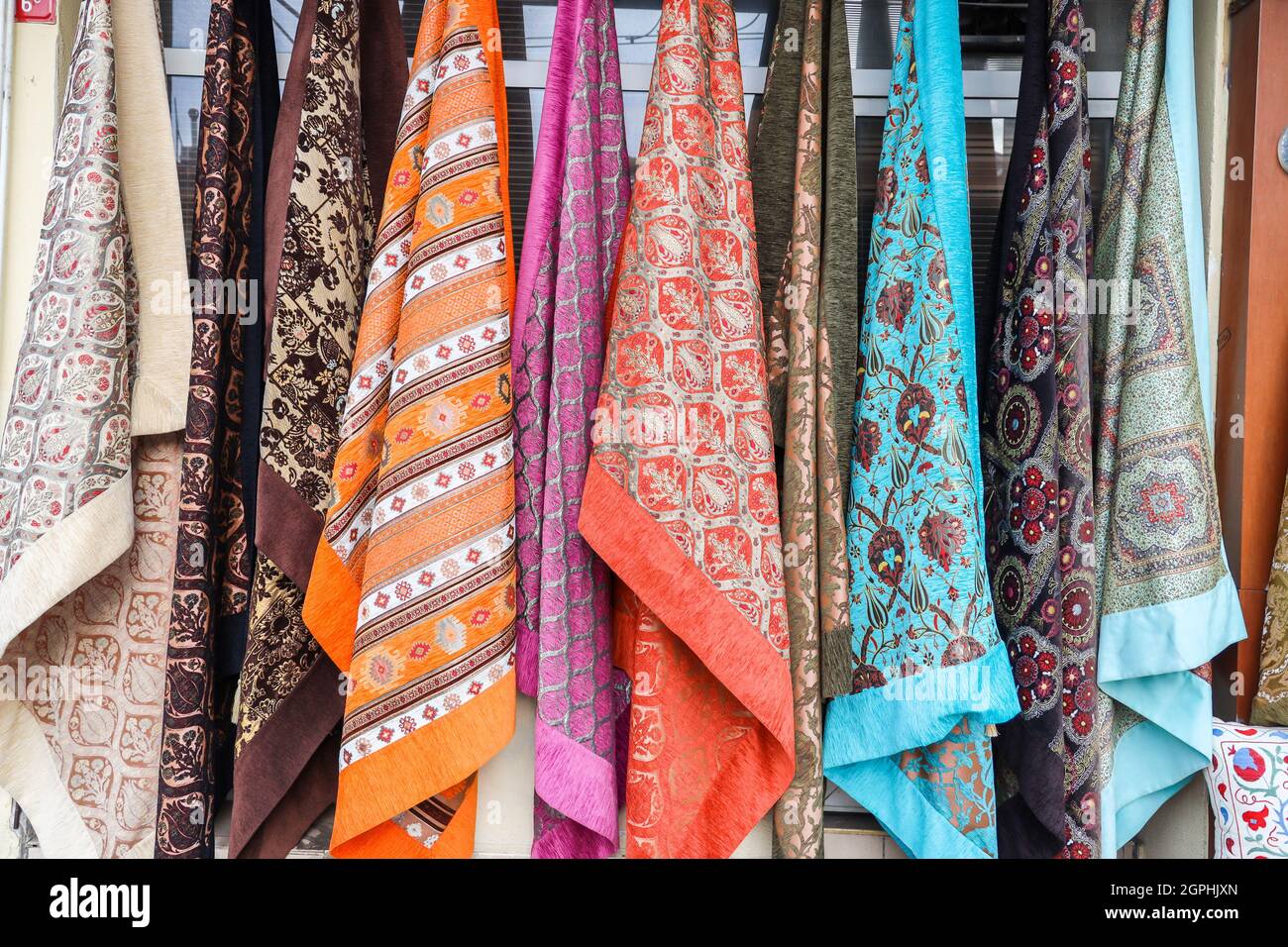 Colorful traditional silk tulle covers hang on the wall in the market ...