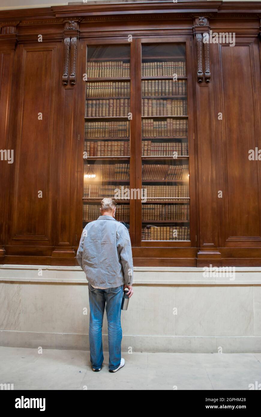 Men is watching at the vintage wooden bookcase Stock Photo - Alamy