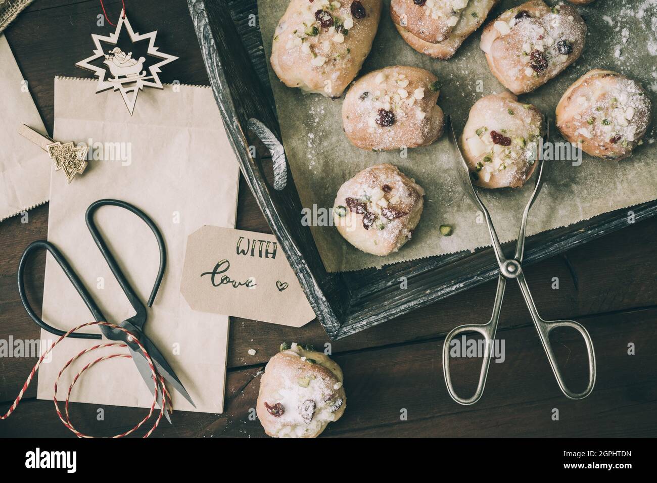 Mini stollen with sugar icing on a wooden tray, paper bags, scissors ...