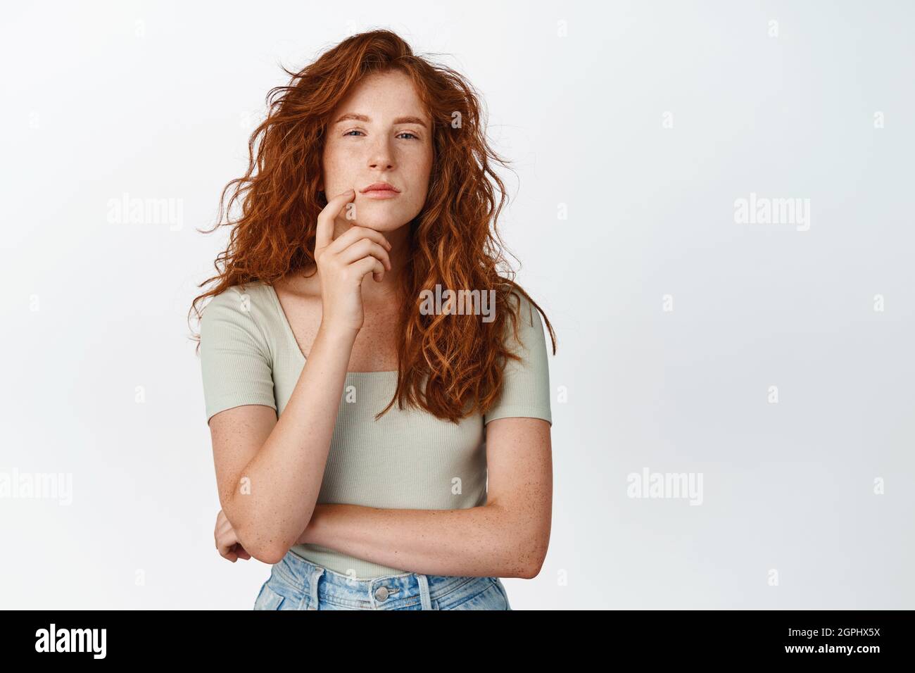 Image of curious ginger girl looking at camera, thinking or making ...