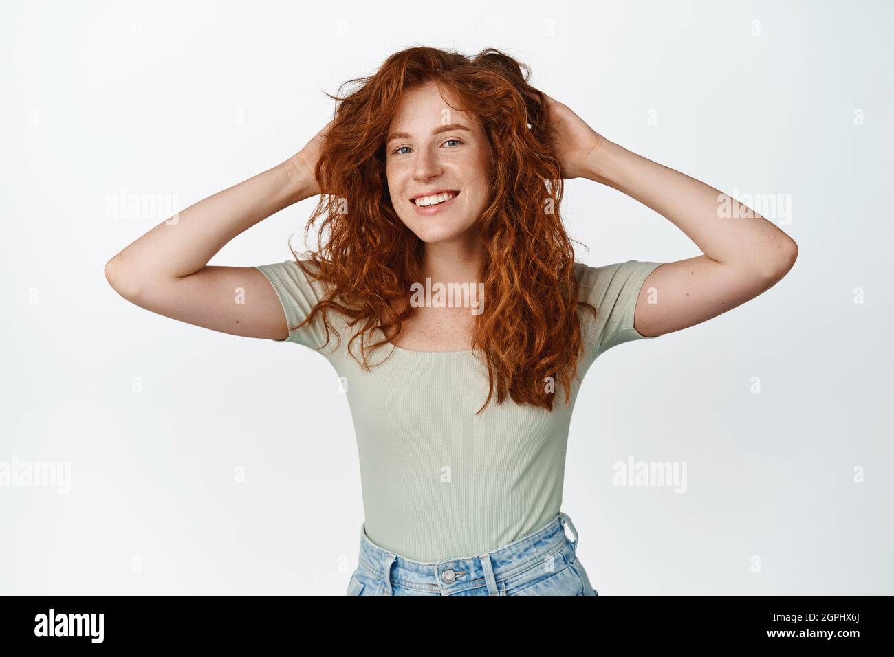 Beautiful girl smiles and looks happy, resting with hands behind head ...