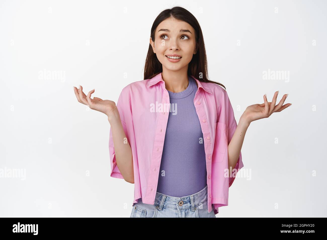 Clueless brunette girl shrugs and looks aside with confused face ...