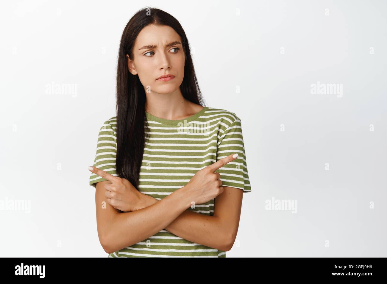 Indecisive brunette woman looking with doubt, pointing sideways, making ...