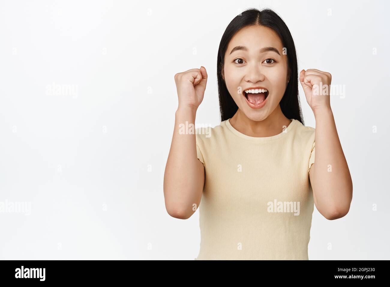 Enthusiastic brunette girl yelling yes, clench fists and celebrating ...