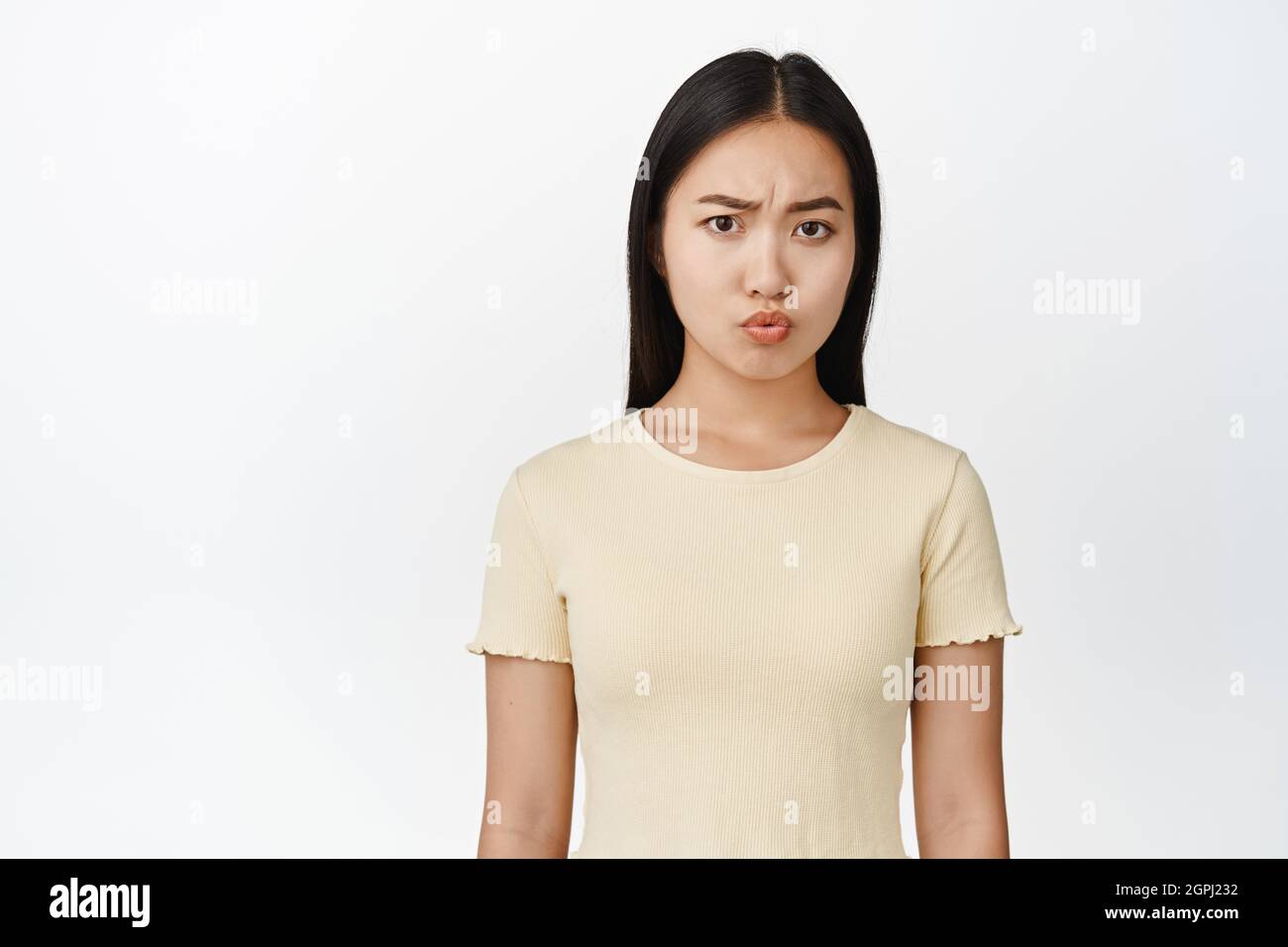 Young asian woman cringing, looking with discomfort at smth strange or ...