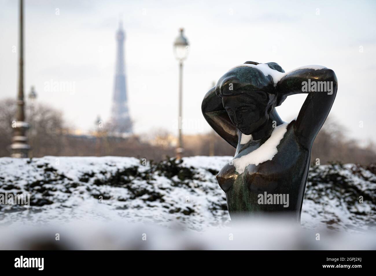 Statue covered with snow with the Eiffel Tower in the background in ...