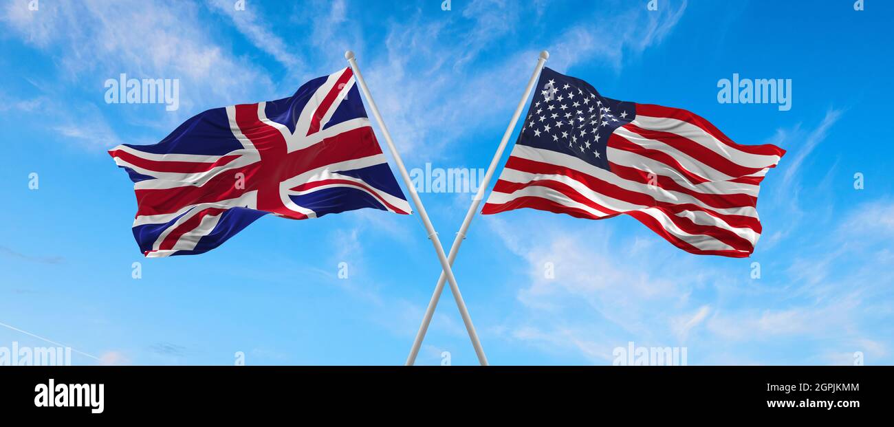 flags of USA and Great Britain waving in the wind on flagpoles against ...