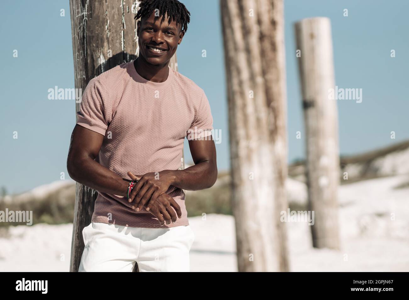 Portrait of handsome happy black man smiling while standing near wooden ...
