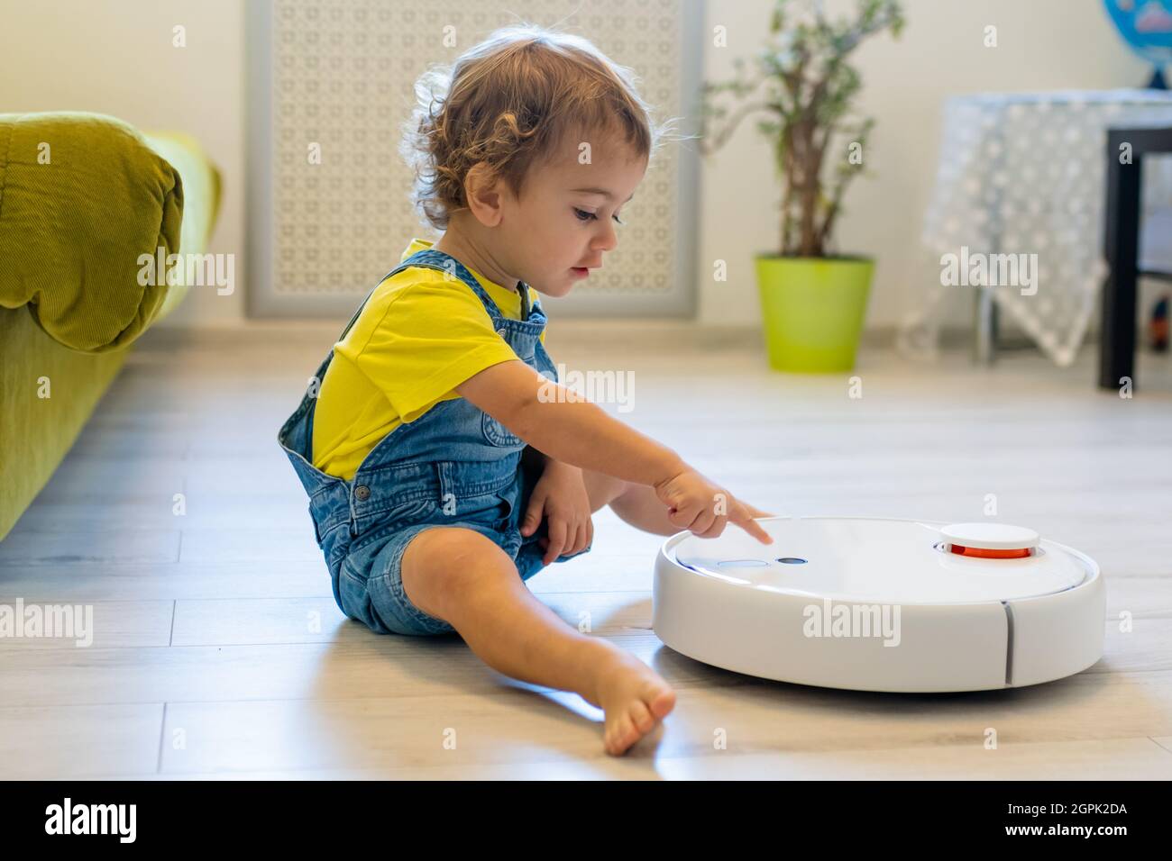 little boy 2 years ago starts a robot vacuum cleaner Stock Photo - Alamy
