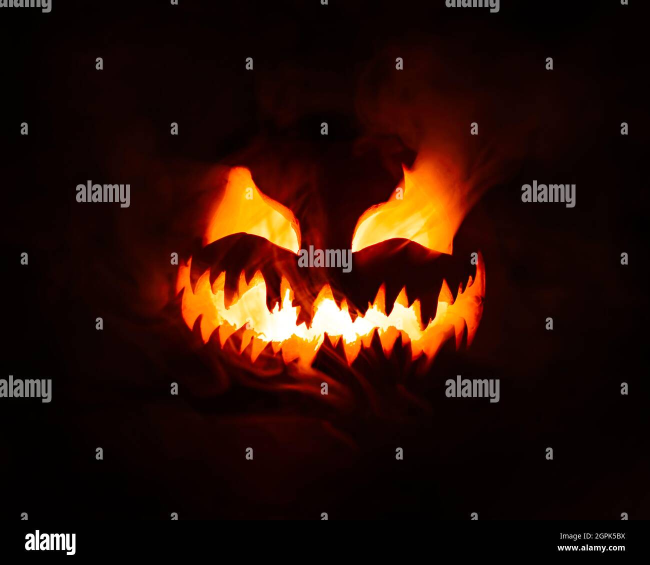 Spooky carved Jack o Lantern glowing a fiery red with thick smoke ...