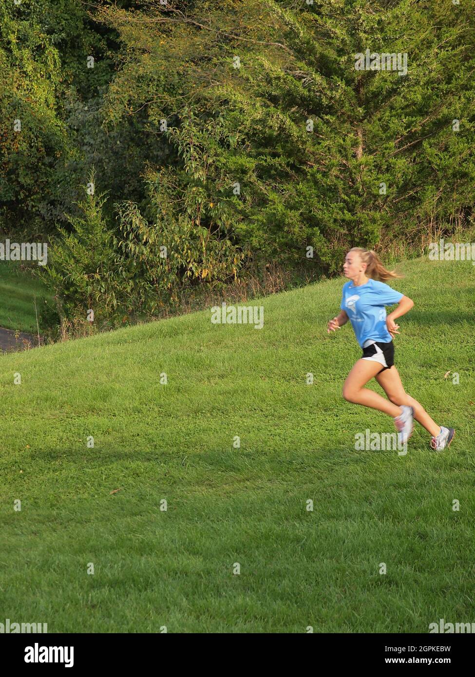 Teen running through green fields during cross country meet hi-res ...
