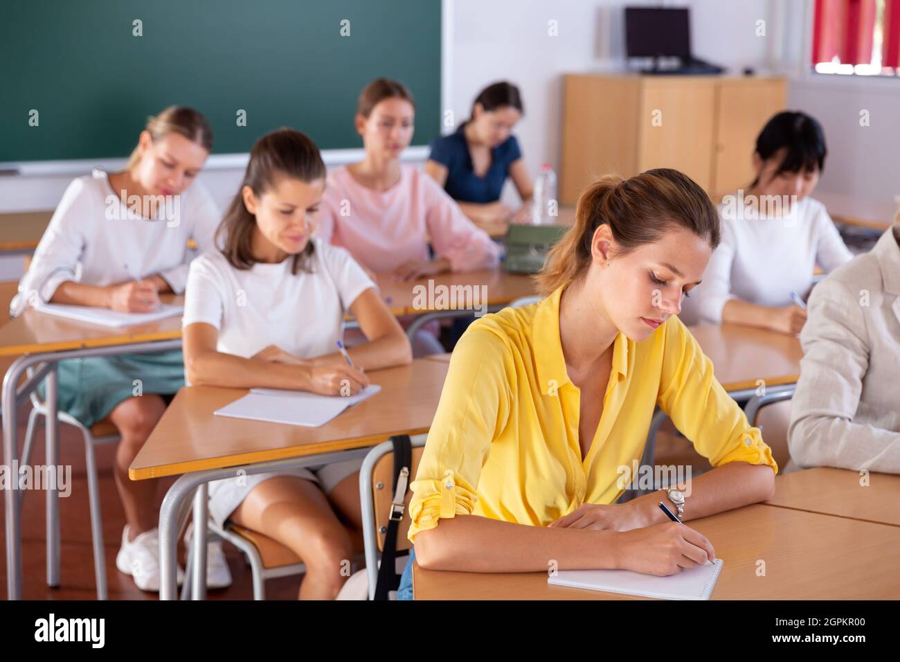 Students writing in notepads during lesson Stock Photo - Alamy