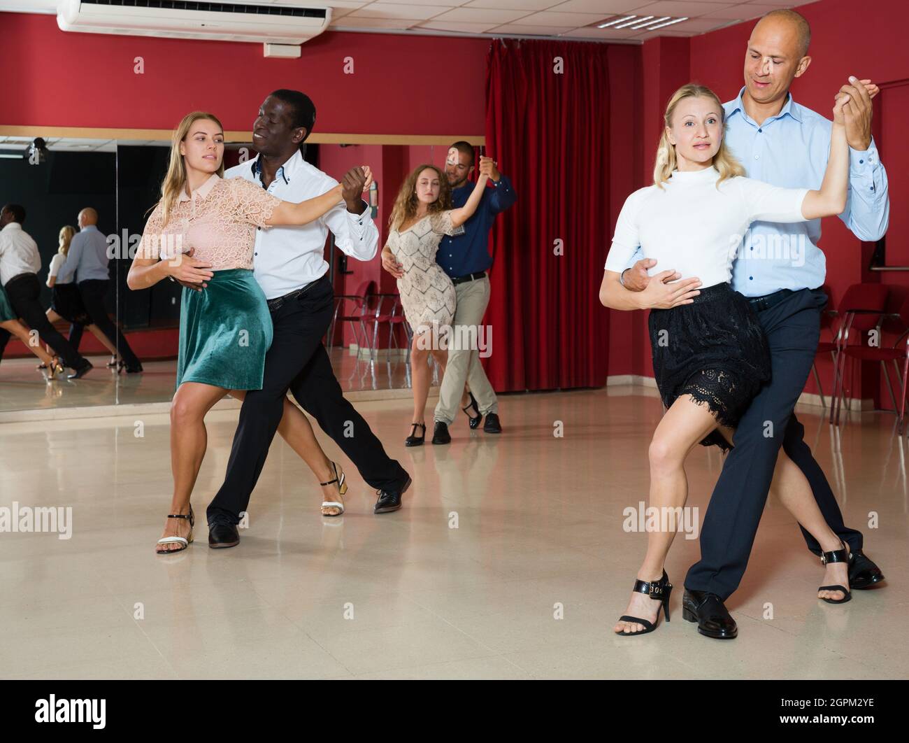 Adult couples dancing salsa dance together in modern studio Stock Photo ...