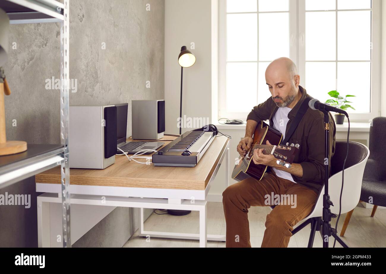 Talented musician playing acoustic guitar and writing new music in his ...