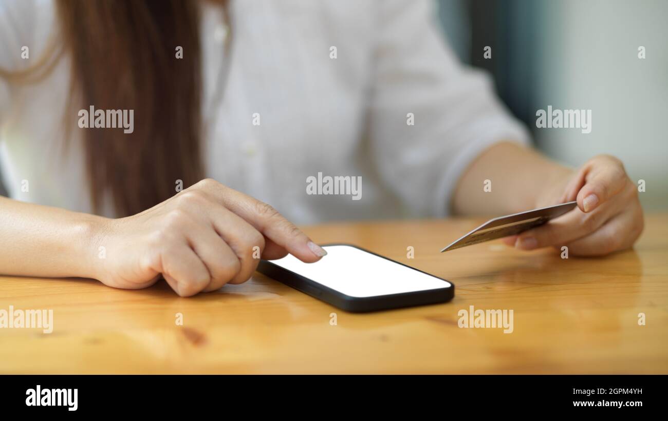 Close up, cropped shot millennial woman holding credit card and enter the details on smartphone ...
