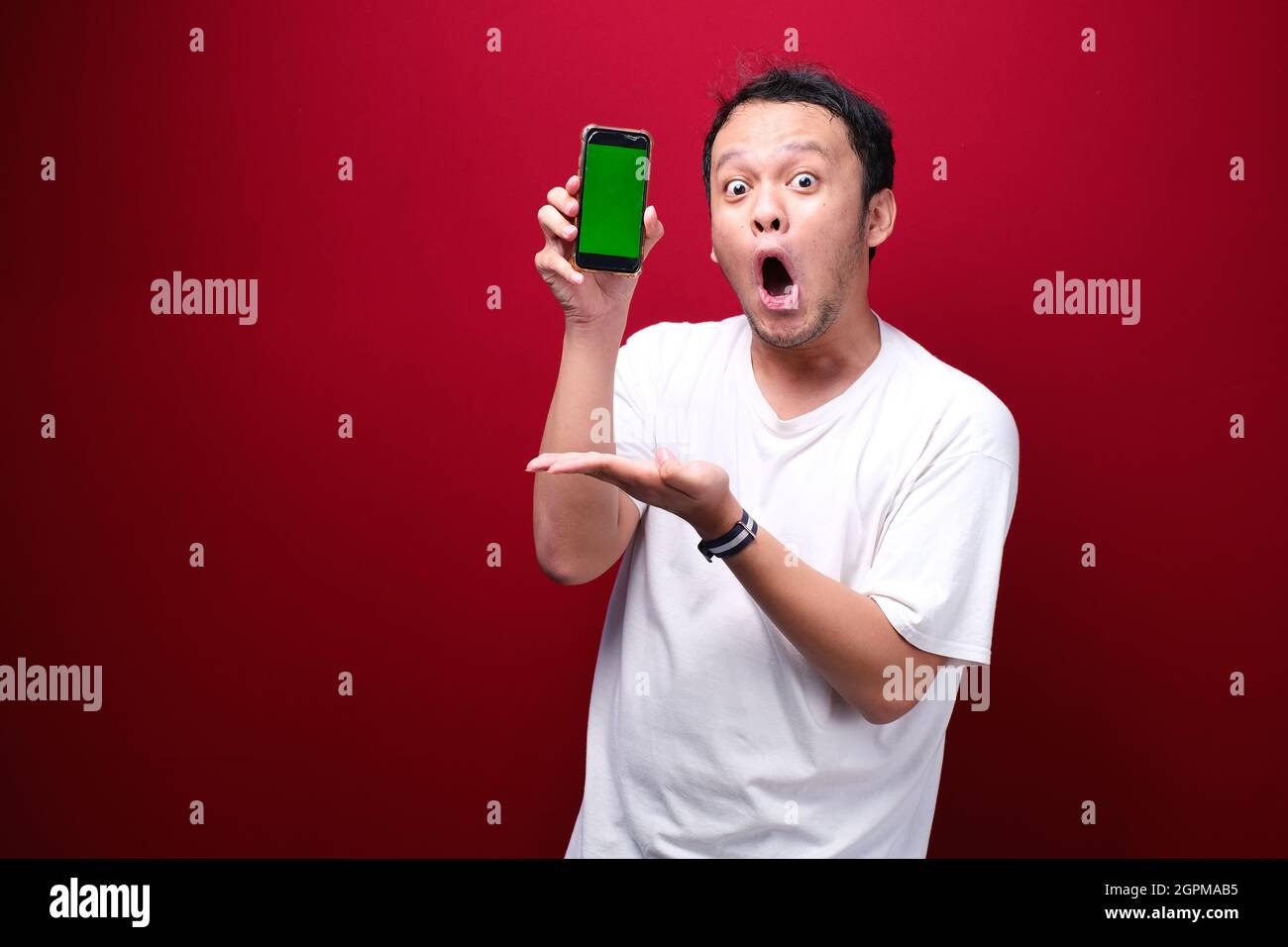 Shock Young Asian man pointing on green blank space on smartphone on ...