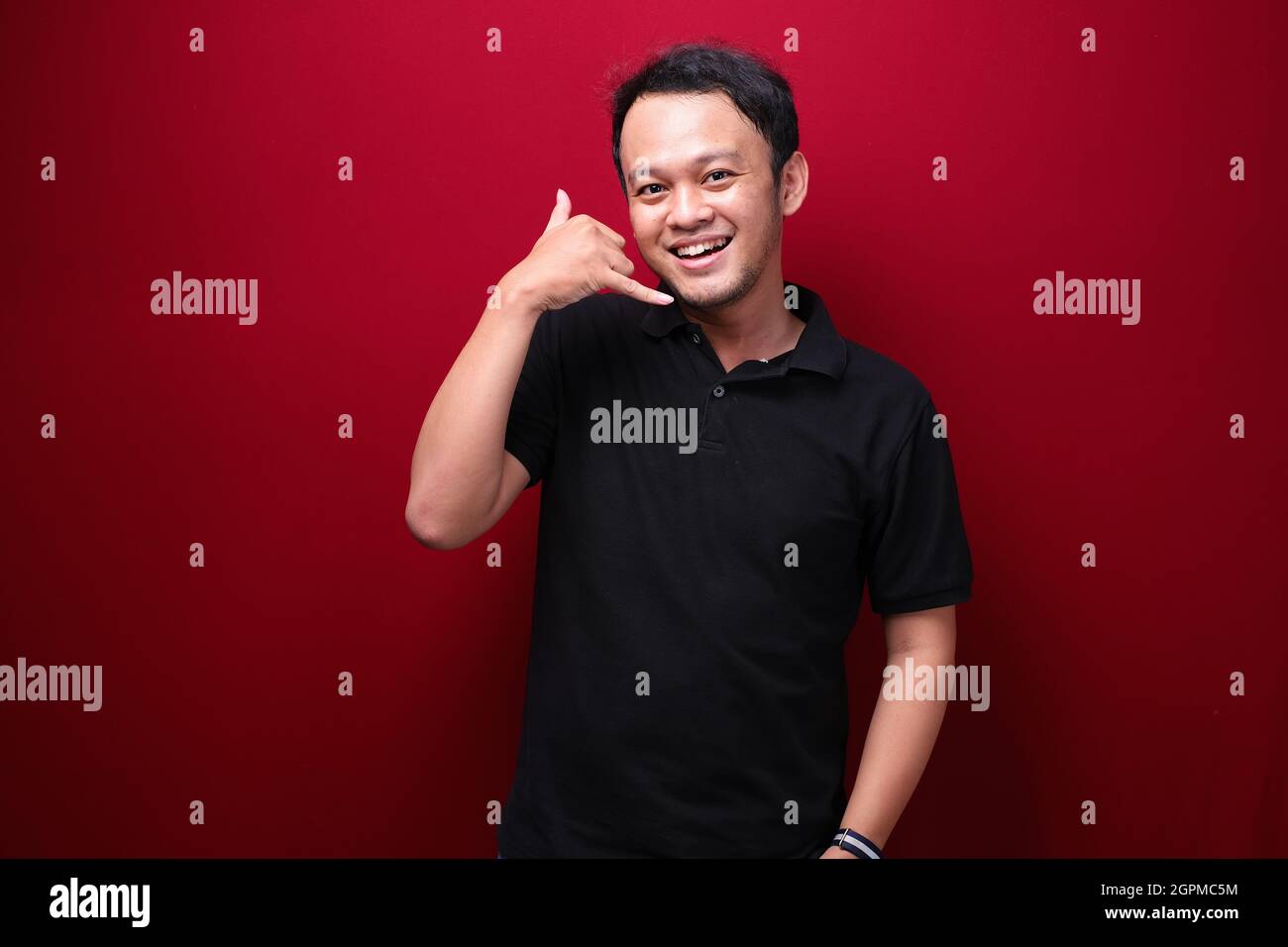 Smiling young asian man with talk or call gesture hand Stock Photo - Alamy