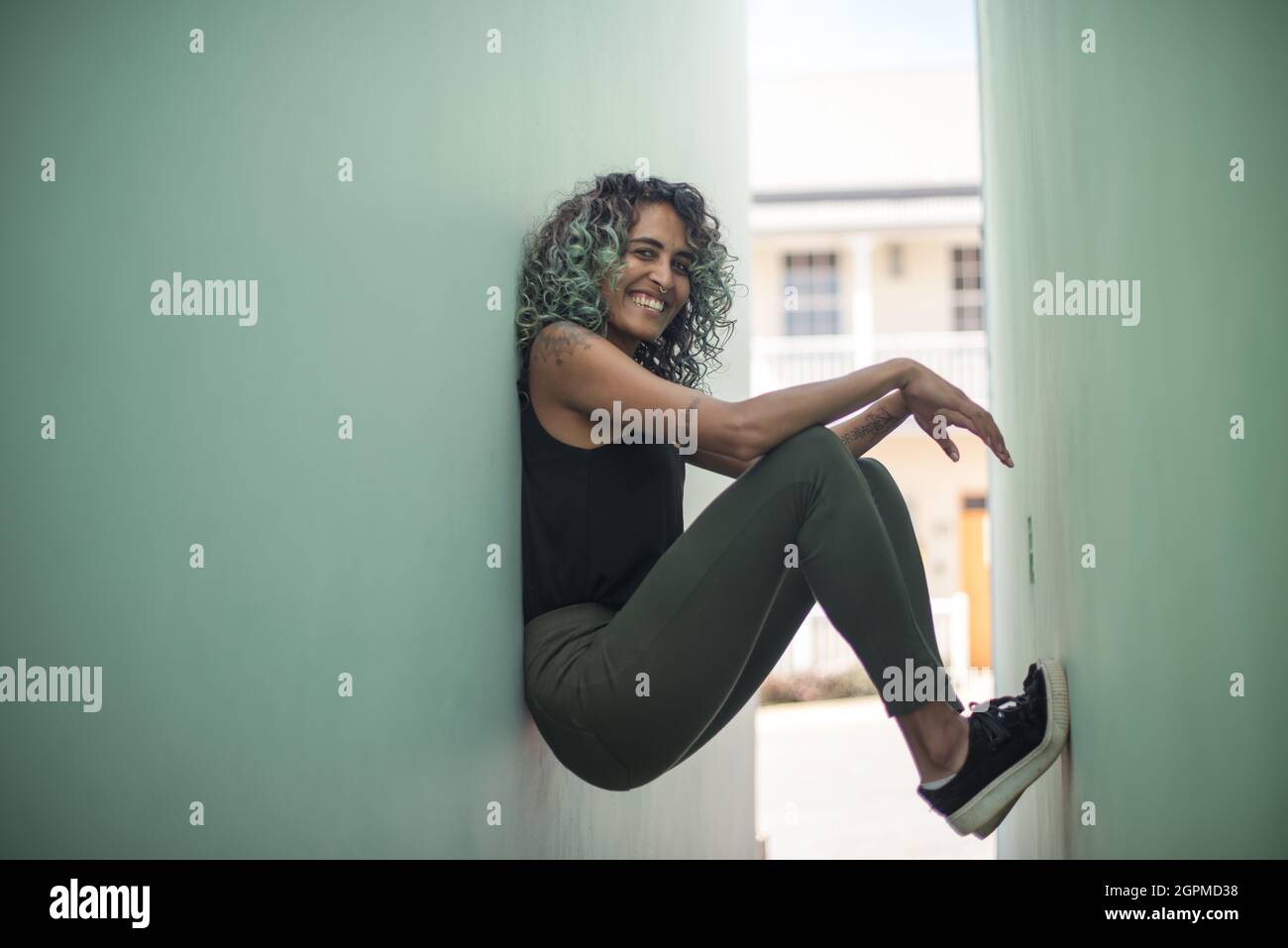 Happy woman leaning against wall Stock Photo - Alamy