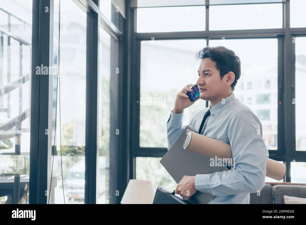 Busy businessman use mobile phone and hands hold dossier and drawing ...