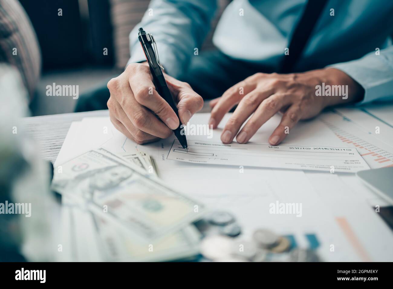 Business man hand writing and signing white blank bank check book and ...