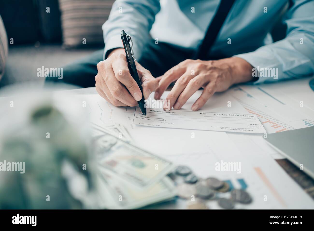 Business man hand writing and signing white blank bank check book and ...