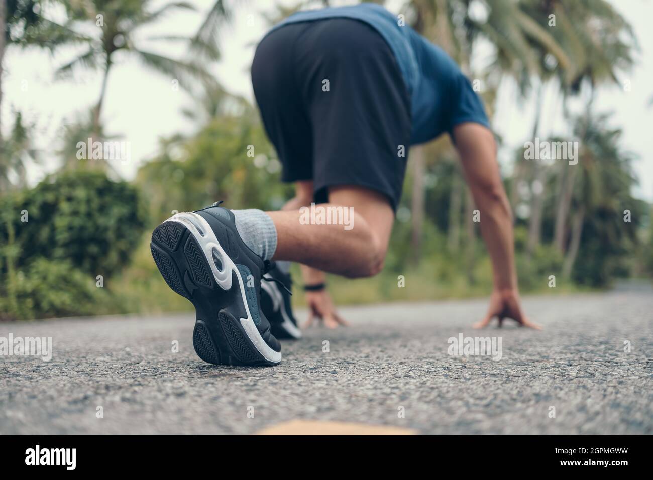Athlete man in running start pose on the road in the forest. Start and ...