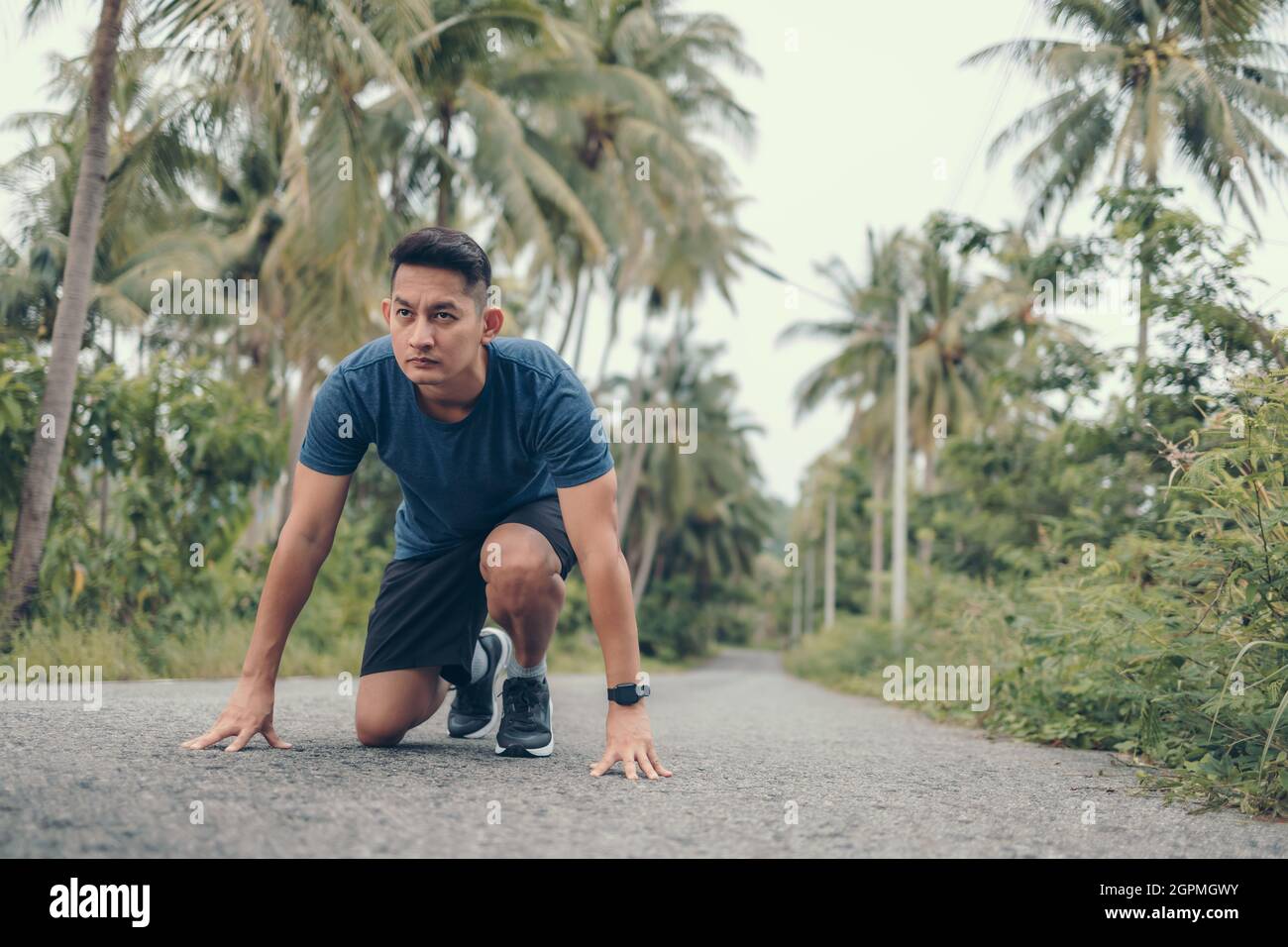 Athlete man in running start pose on the road in the forest. Start and ...