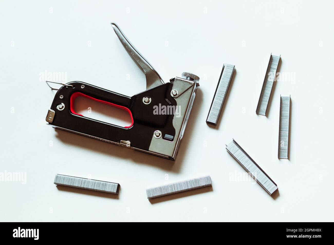 Furniture construction stapler next to staples on a white background ...