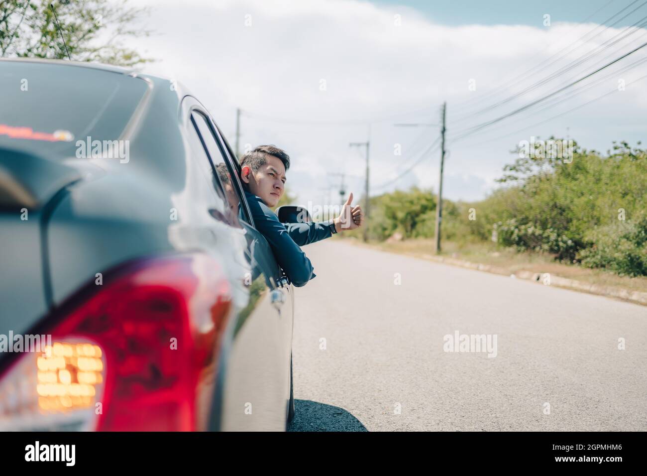 hand giving a thumbs up sign throw the window of a car broken on the ...