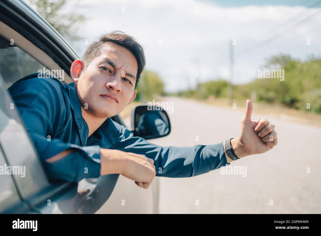 hand giving a thumbs up sign throw the window of a car broken on the ...