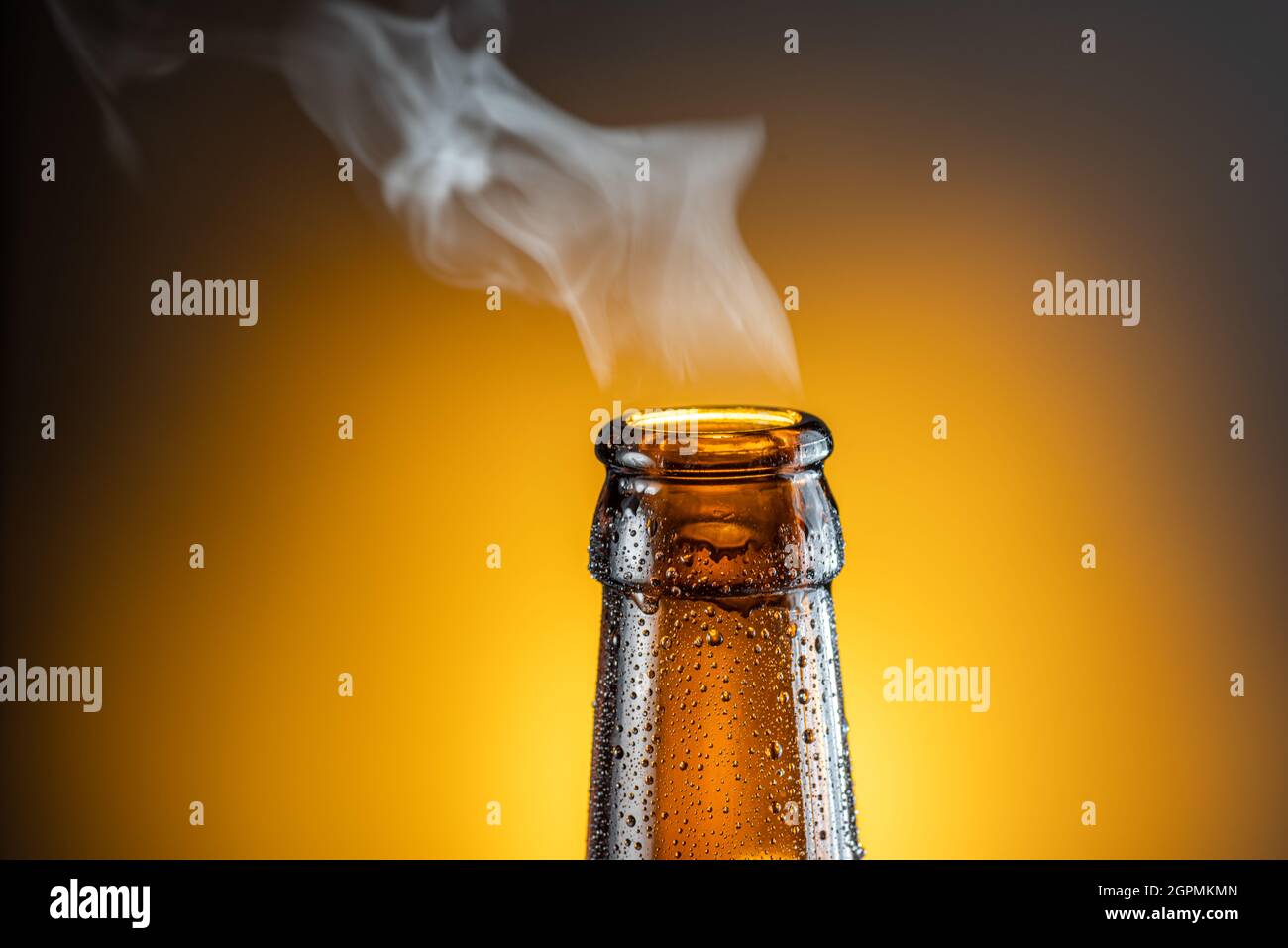 Opened bottle of cold beer and gas output isolated on a yellow ...