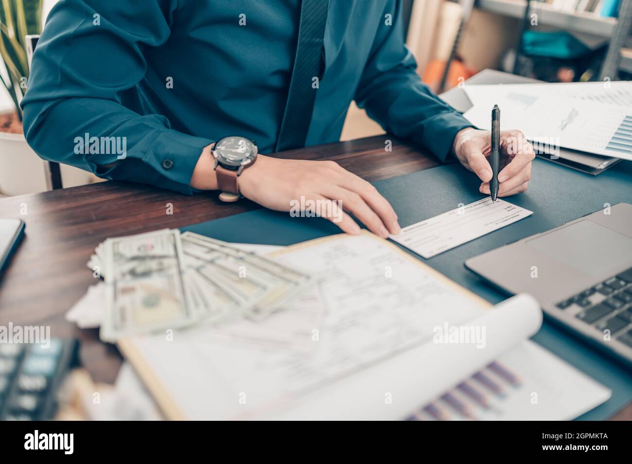 Business man hand writing and signing white blank bank check book and ...