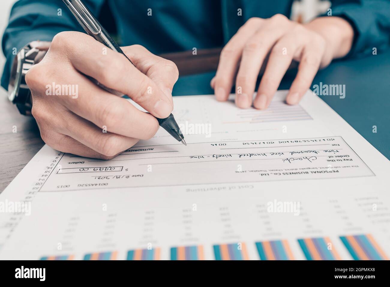Business man hand writing and signing white blank bank check book and ...