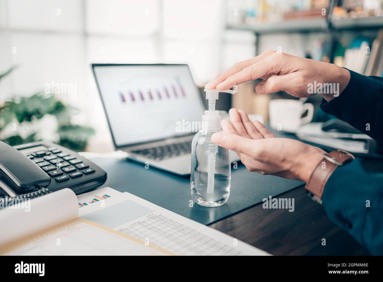 Man pressing hand sanitiser on his desk to wash his hands to prevent ...