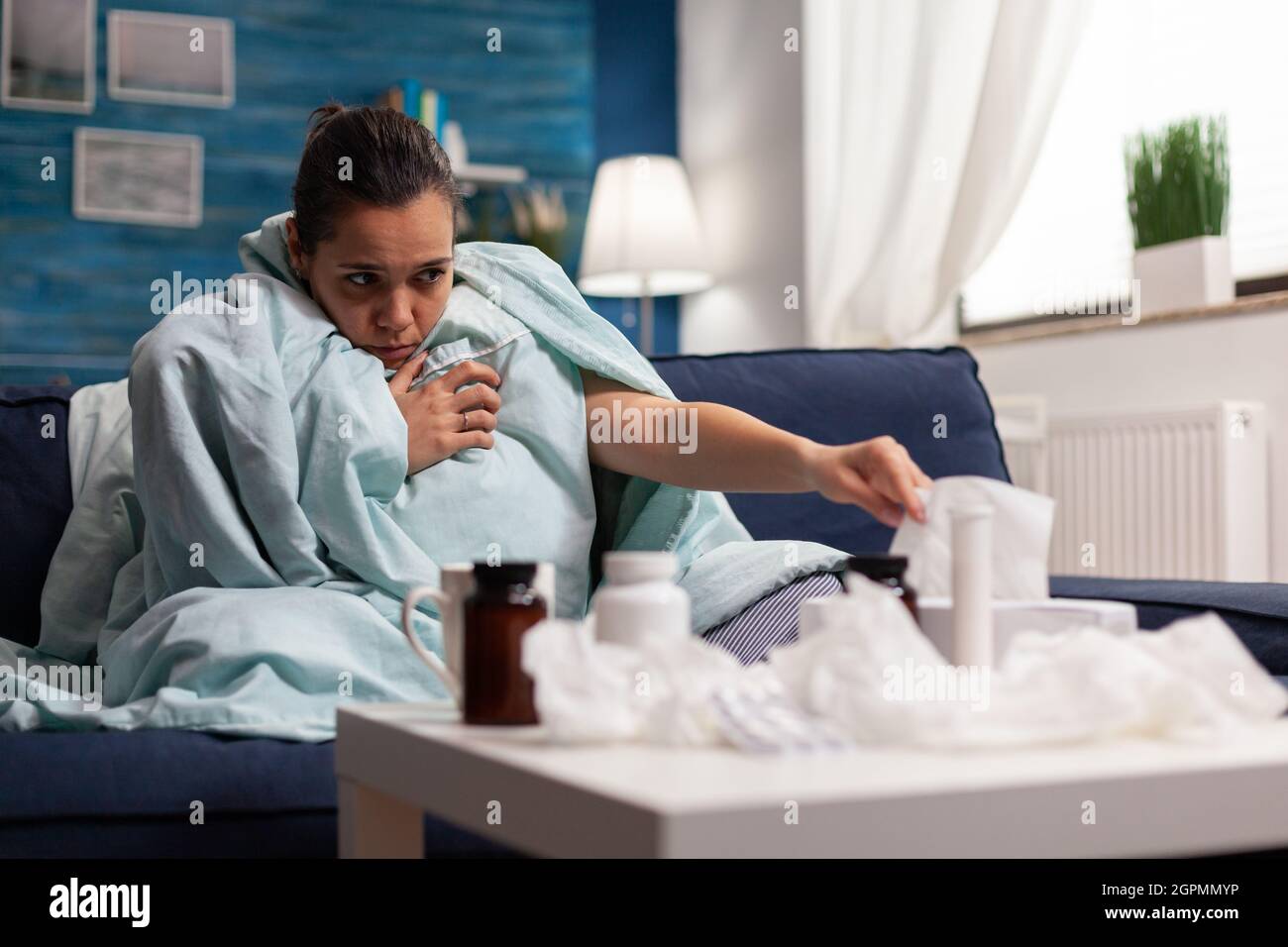 Woman with flu symptoms sitiing at home ill on couch suffering. Young ...