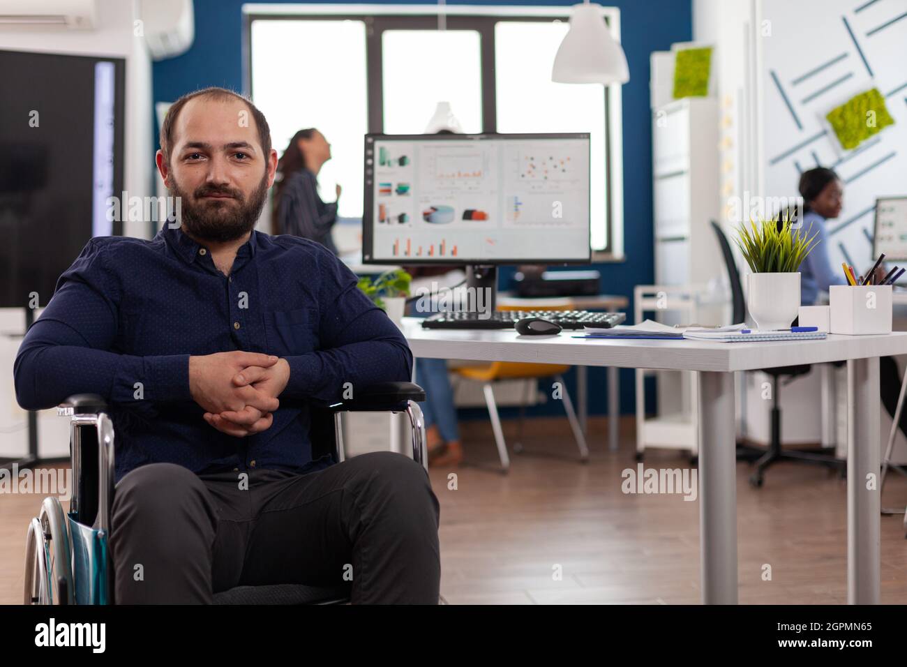 Portrait of paralyzed businessman in wheelchair looking into camera in ...