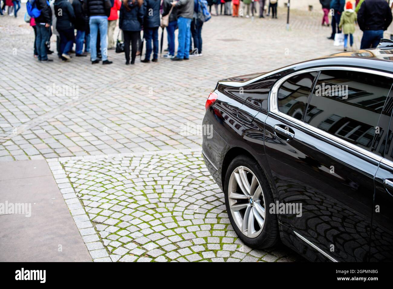 Side view of luxury black BMW car parked on cobblestone pavement road ...