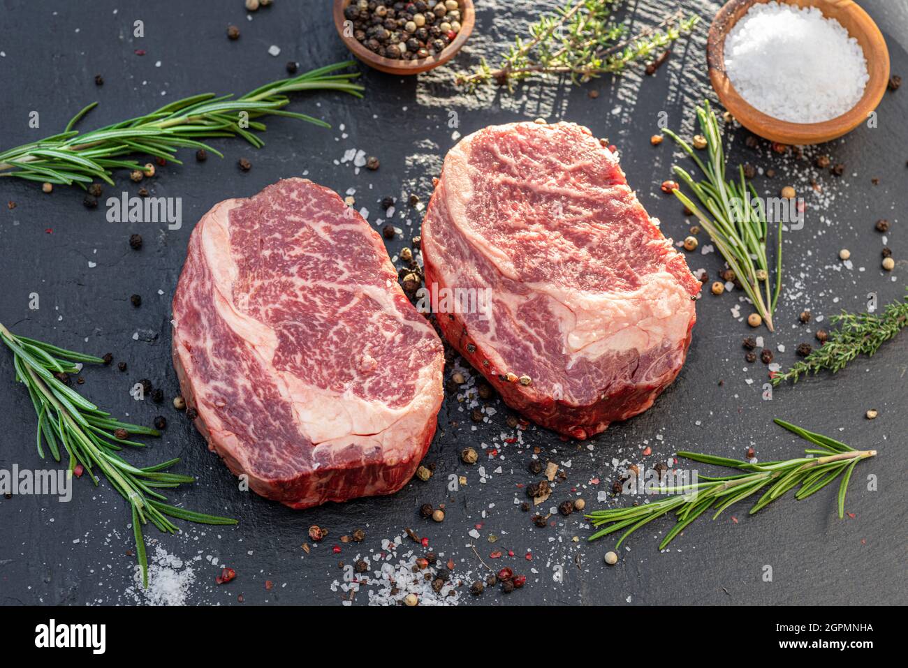 Raw Ribeye steaks with salt and herbs on grey board. Top view Stock ...