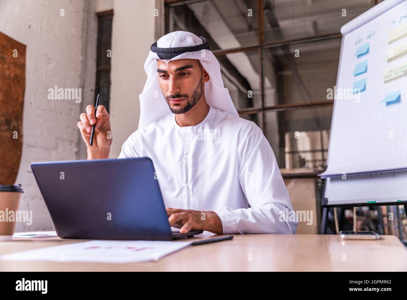 Arab businessman wearing traditional emirates kandura at work in a ...