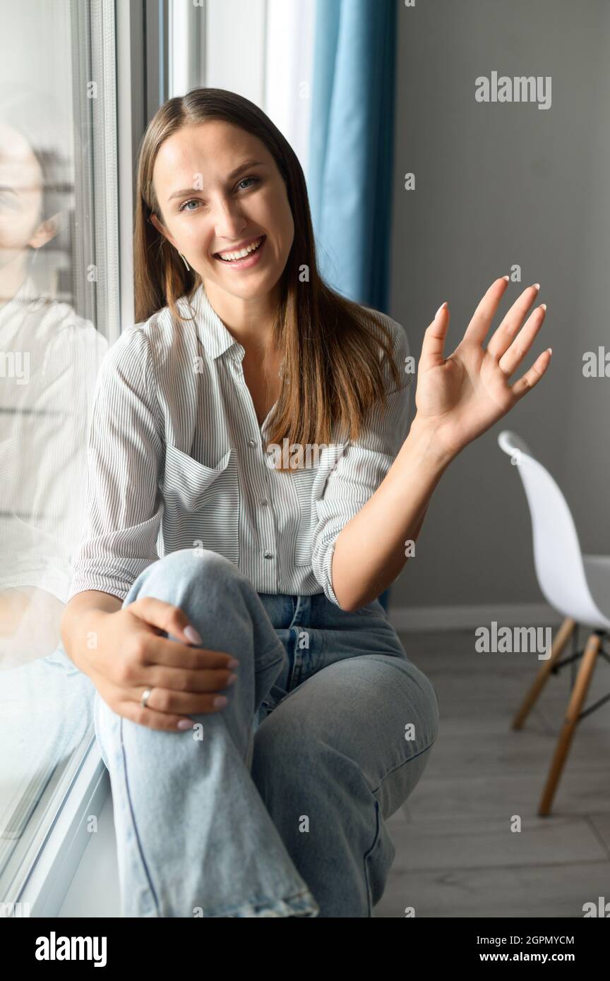 Glad to see you. Friendly adorable young woman joyfully waving at the ...