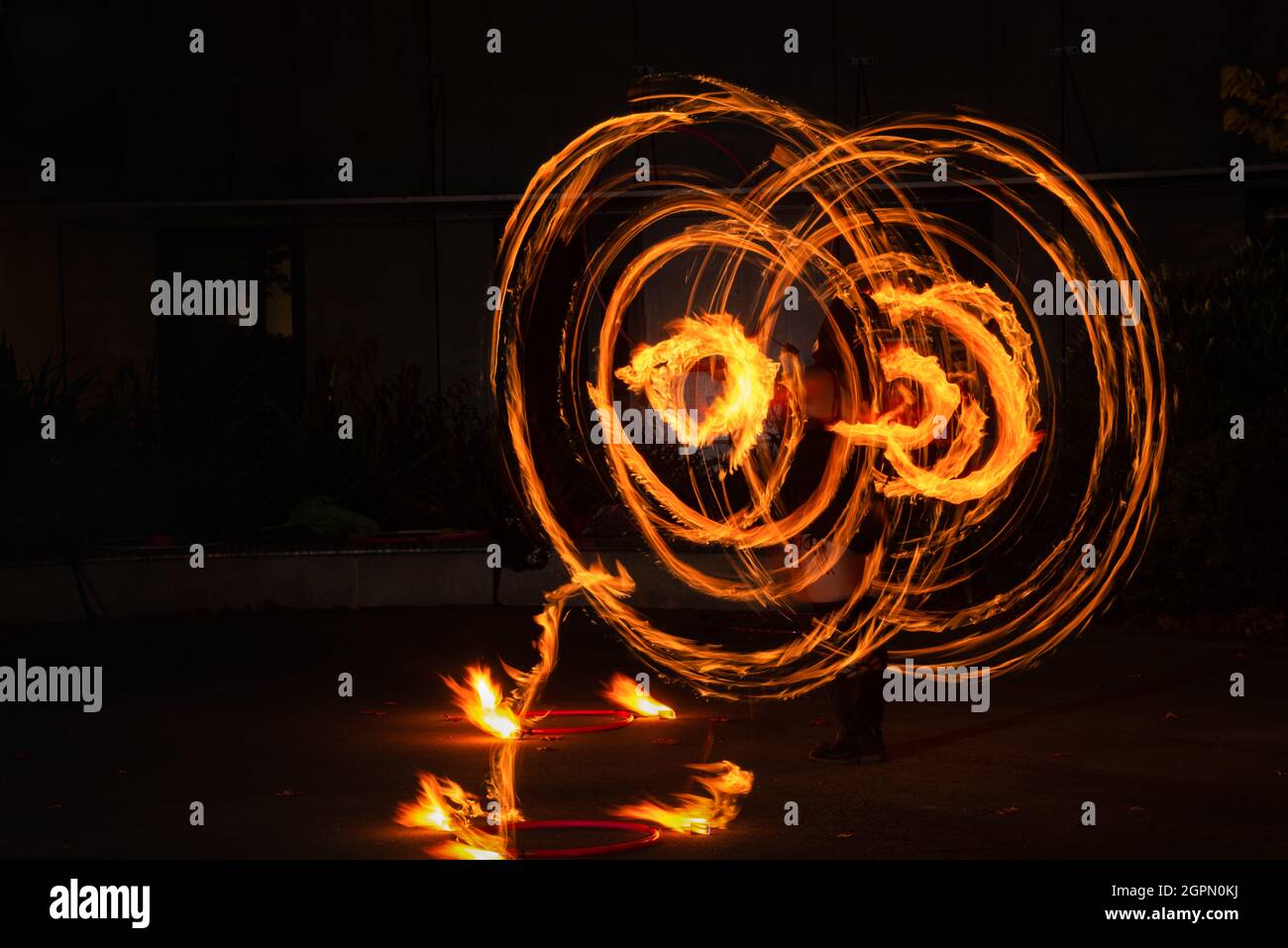 Street artist juggling with burning Hula Hoop at fire performance. Long ...