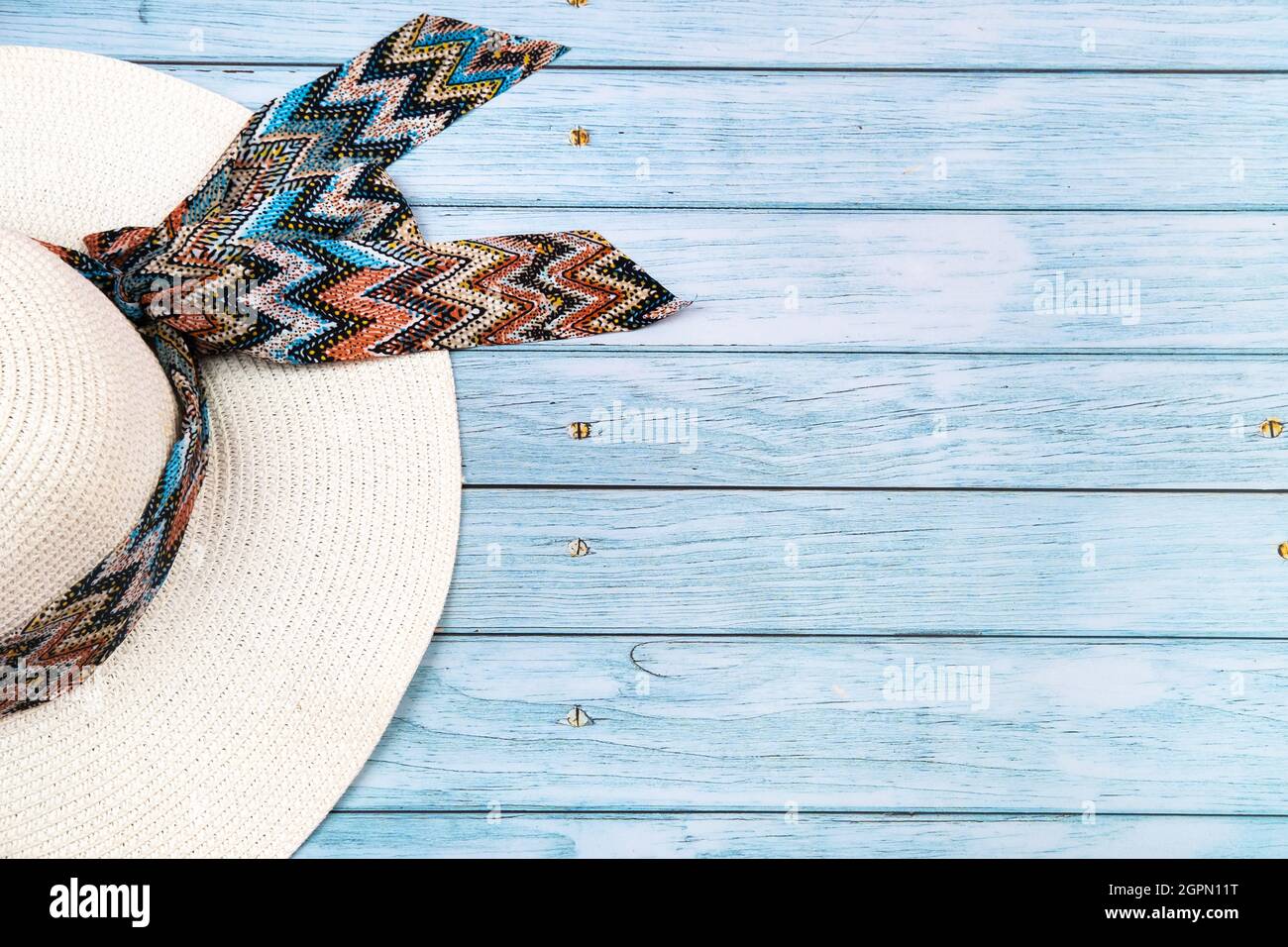 Top view of a straw white hat lying on a blue wooden background.The ...