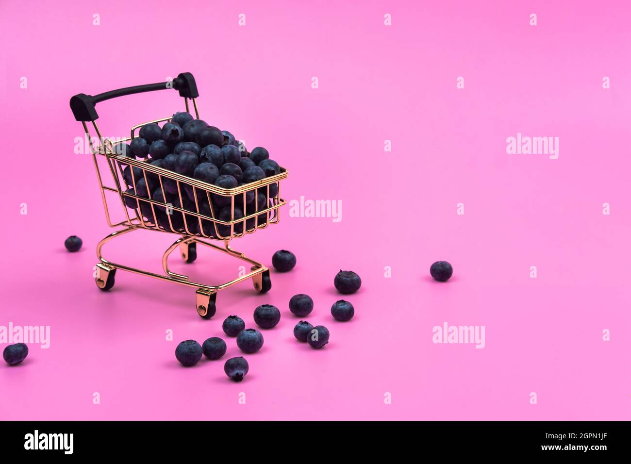 Blueberries in a grocery cart on a pink background. Scattered ...